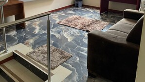 Uma sala de estar moderna com televisão de tela plana, um armário de madeira, uma mesa vermelha e uma janela grande com vista.