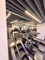 Uma academia com várias esteiras, máquinas de musculação e diversos equipamentos de exercício.