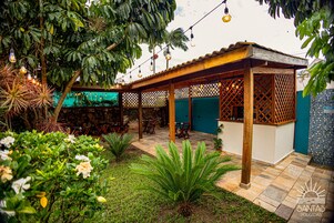 Uma área externa coberta com pérgola de madeira, assentos e luzes de corda.