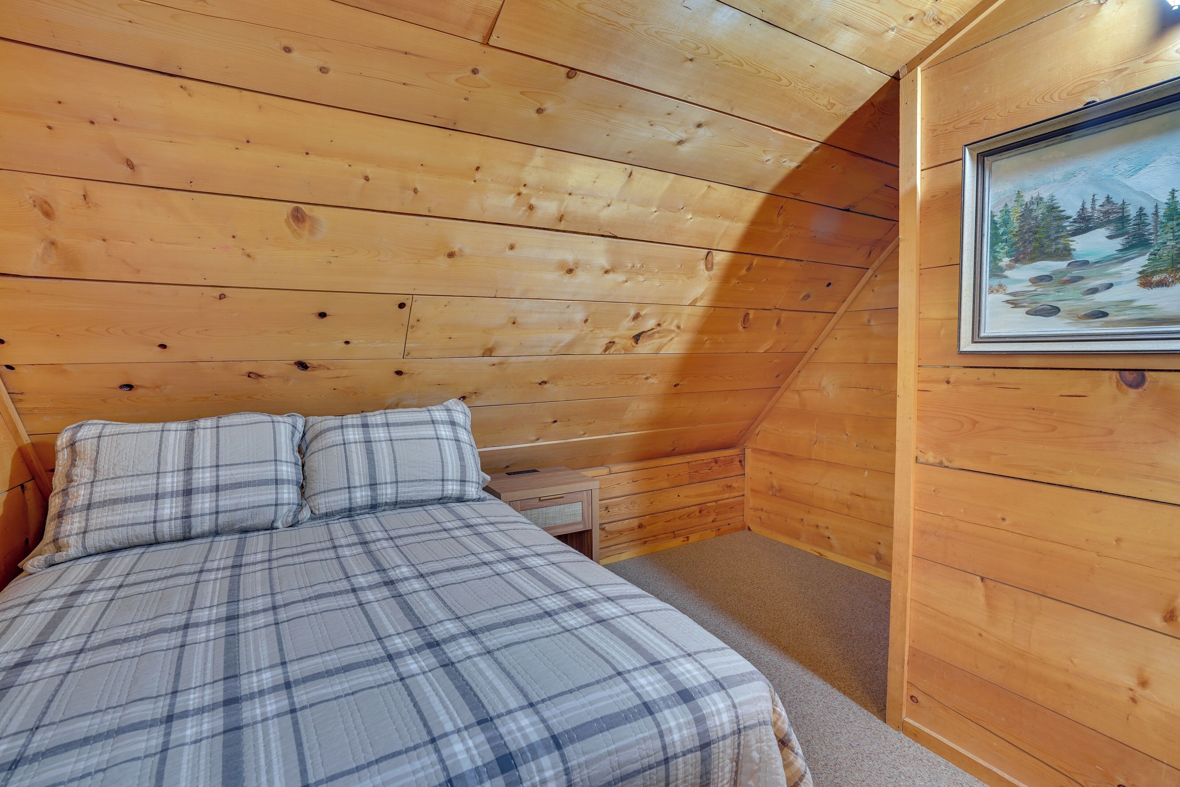 Quarto de cabana de madeira com cama, almofadas e um quadro na parede.