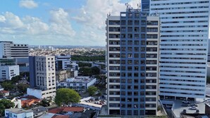 Um edifício alto com vários andares, rodeado por outros edifícios e um céu limpo.