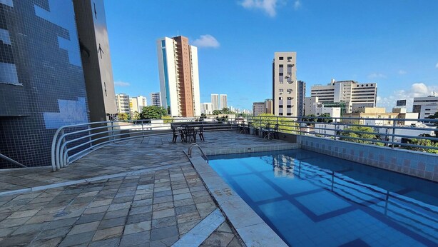 Piscina no terraço com vista para edifícios da cidade.