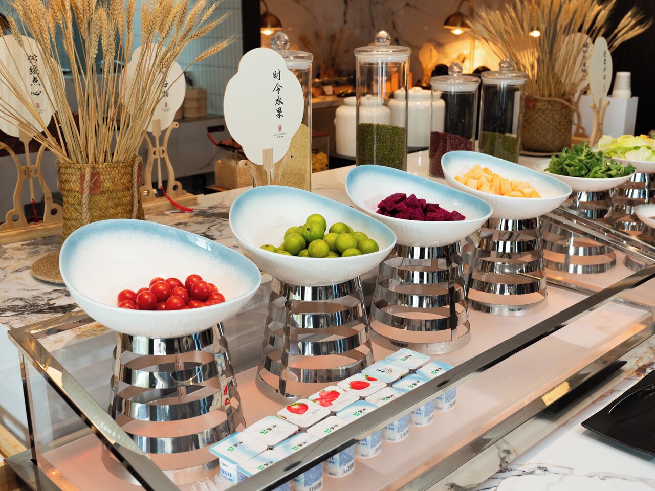 Um buffet com diversos alimentos dispostos em tigelas e recipientes, sobre um balcão de mármore.