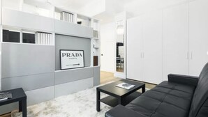 Uma sala de estar moderna com um sofá de couro preto, uma mesa de centro e uma estante cinza com a marca Prada.