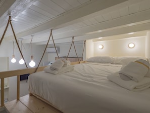 Quarto com cama, lâmpadas penduradas e teto de madeira.