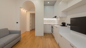 Cozinha moderna com armários brancos, forno embutido e uma grande televisão de tela plana.