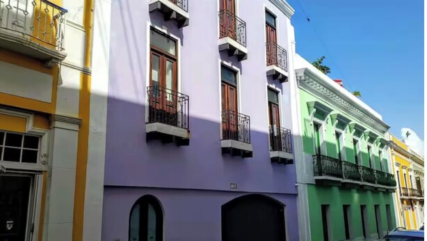 Um edifício de vários andares com varandas, entrada de garagem e céu azul.