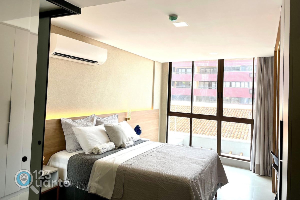 Quarto de hotel com cama, janela e ar condicionado.