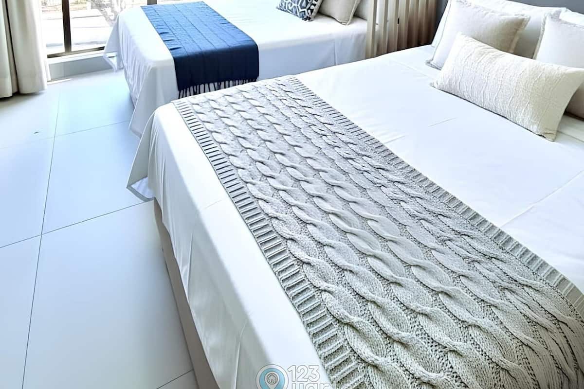 Quarto de hotel com duas camas, janelas amplas e ar condicionado.