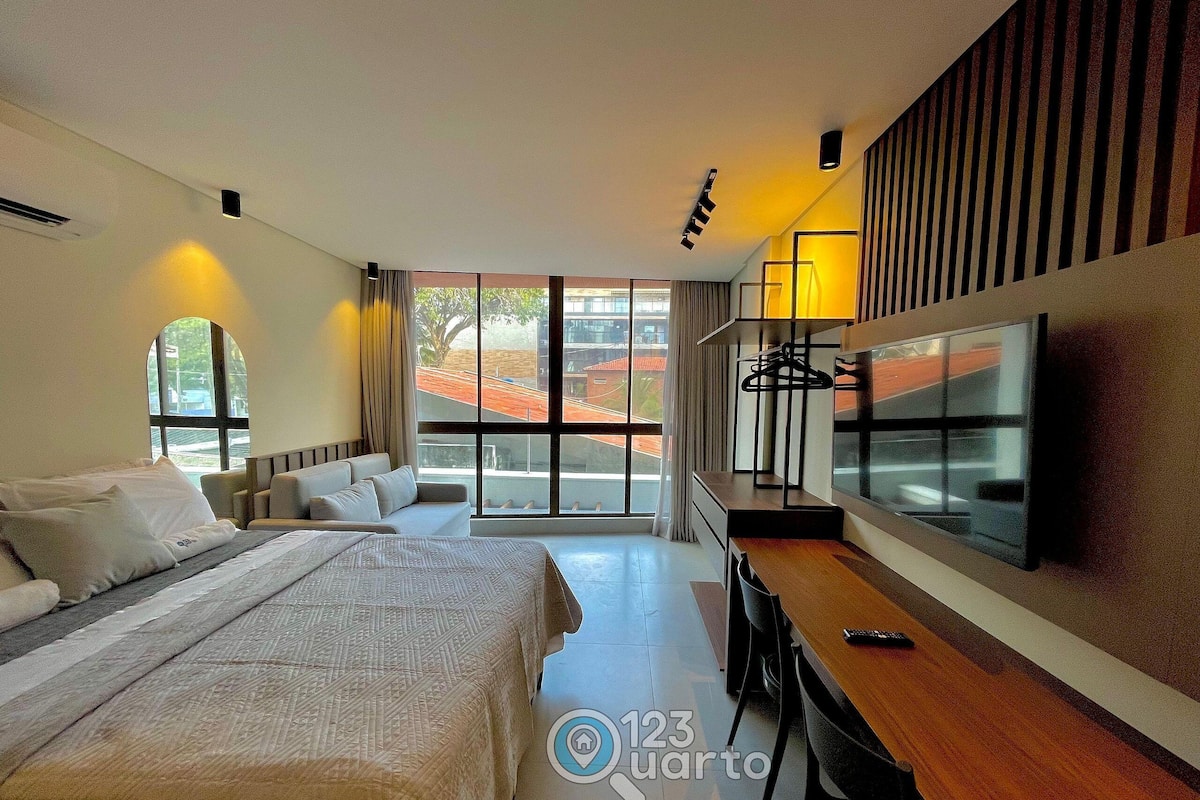 Quarto de hotel moderno com uma cama grande, uma escrivaninha e uma TV.