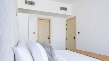 Quarto de hotel com uma cama, duas portas e uma parede branca.