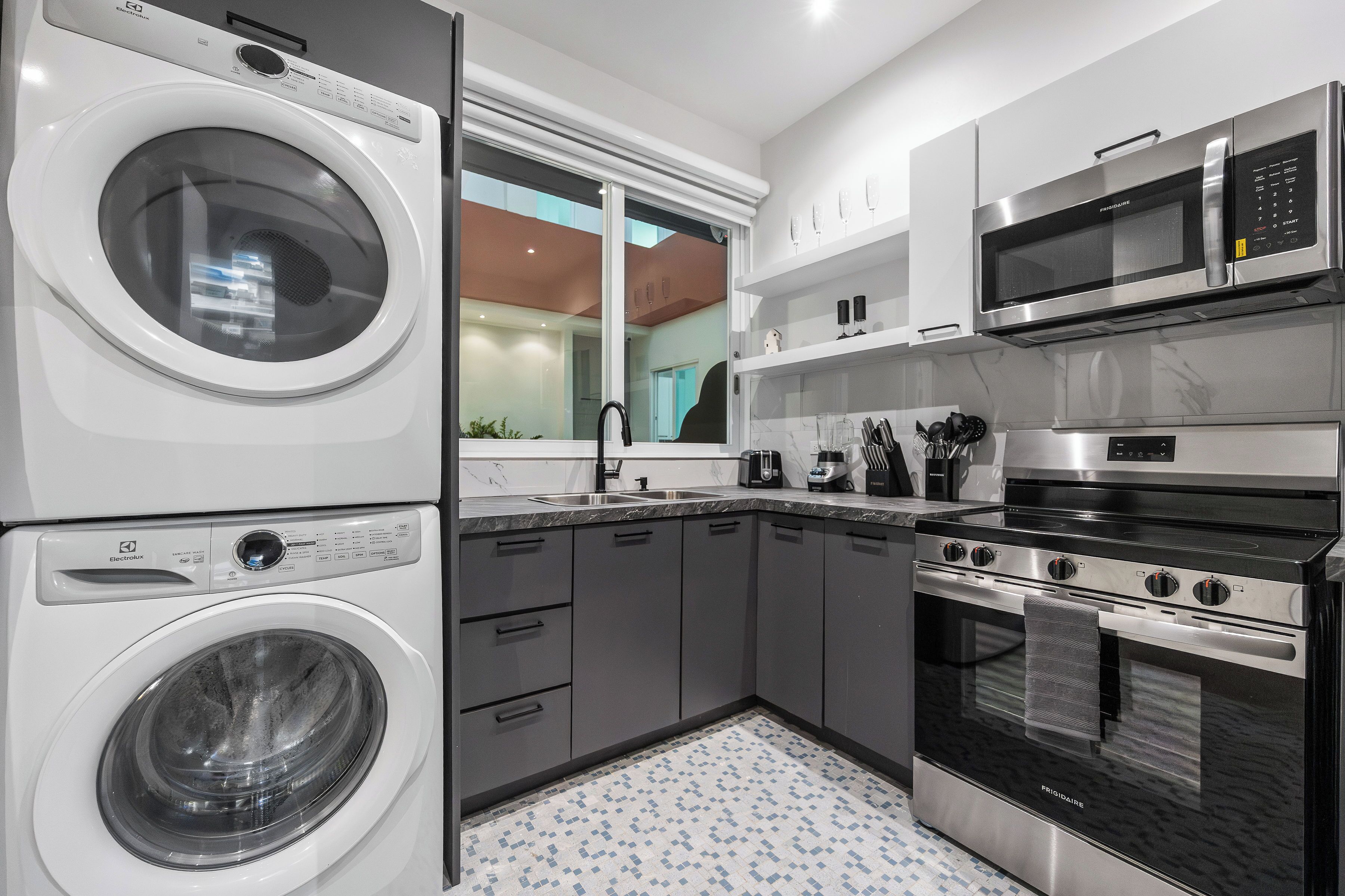 Cozinha moderna com máquina de lavar e secar embutidas, eletrodomésticos de aço inoxidável e painel de azulejos.