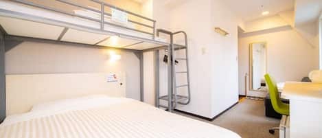 Quarto de hotel com beliche, escrivaninha e cadeira.
