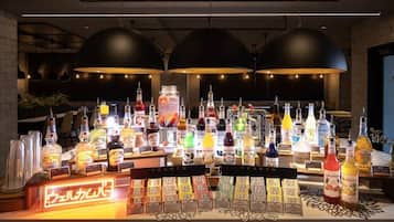 Área de bar com diversas garrafas e copos, iluminada por luzes no teto.