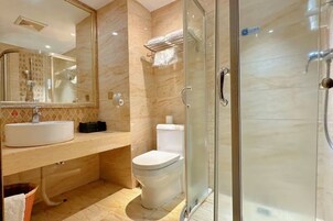 Uma casa de banho moderna com um espelho grande, lavatório, sanita e cabine de duche com parede de vidro.