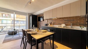 Cozinha moderna com área de jantar, destacando um painel de backsplash de tijolos, armários pretos e uma janela ampla com vista para uma varanda.