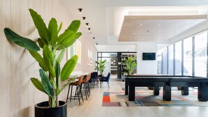 Espaço moderno em ambientes internos com mesa de bilhar, área de estar e plantas em vasos.