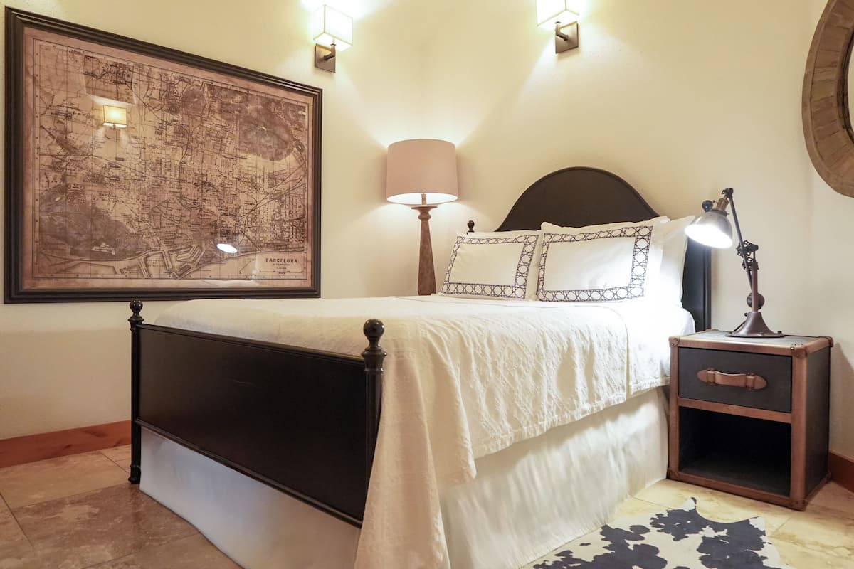 Quarto bem organizado com cama, mesa de cabeceira, abajur e um mapa na parede.