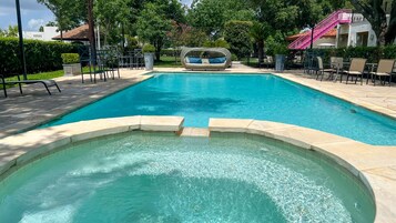 Uma piscina clara com espreguiçadeiras e área de estar.