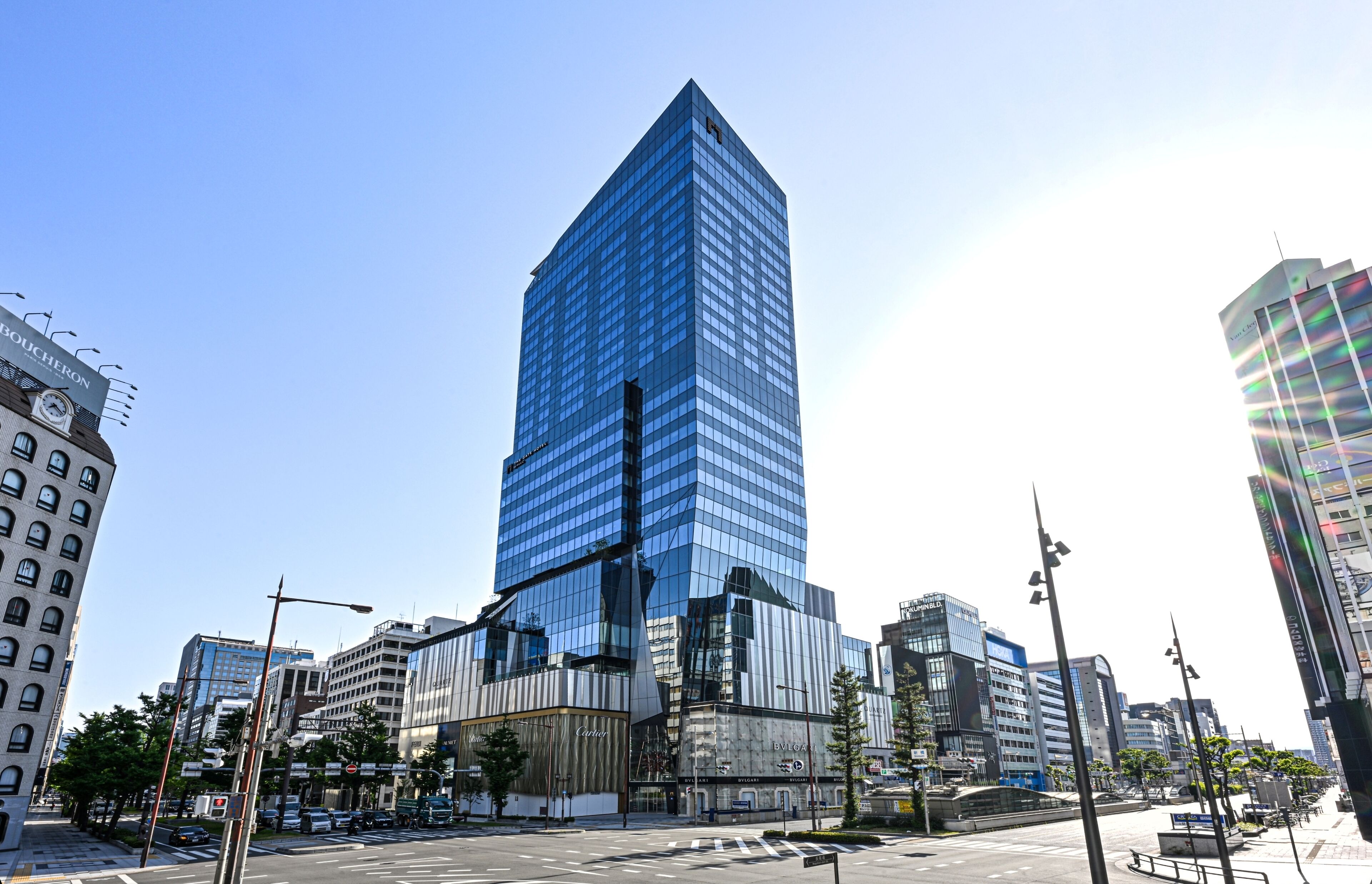 Um edifício moderno e imponente com fachada de vidro, cercado por outros edifícios comerciais.
