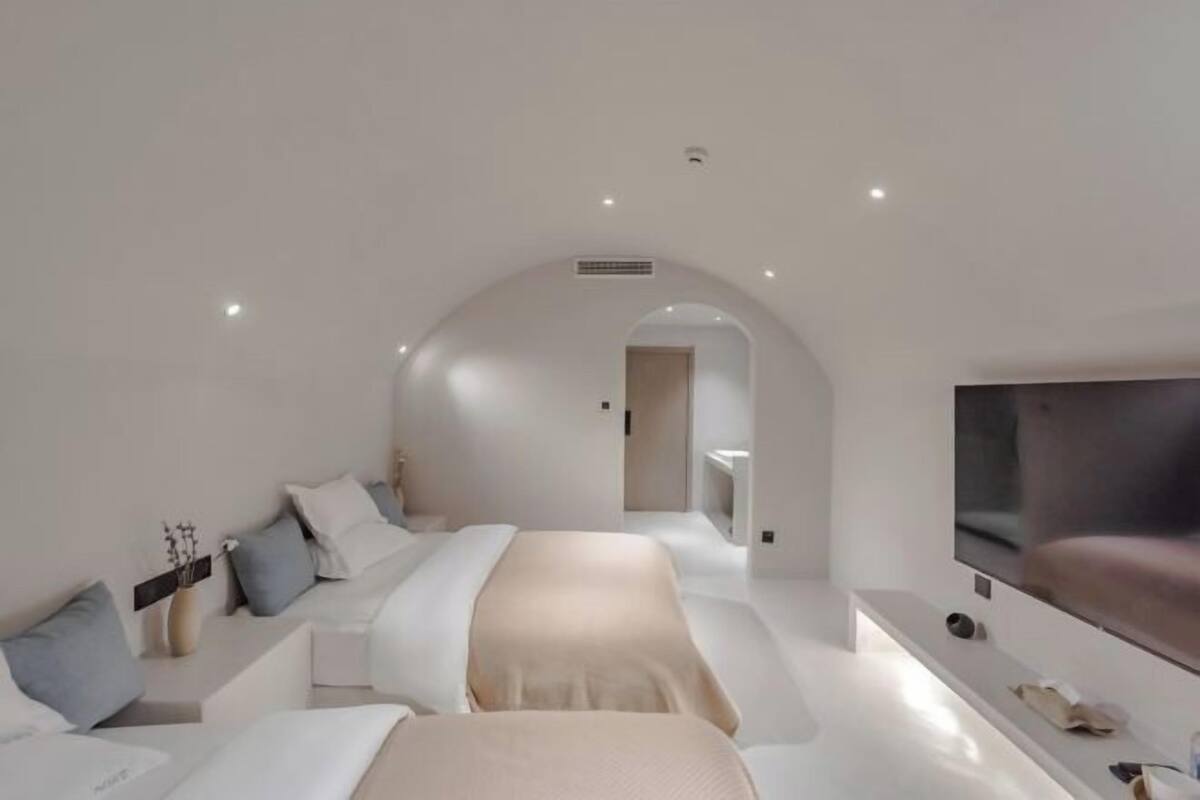 Quarto de hotel moderno com uma cama grande, uma TV e um design minimalista.