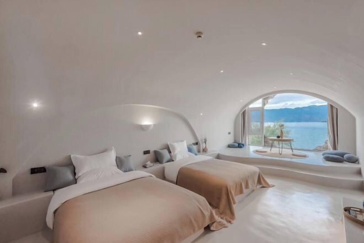 Quarto moderno com duas camas, uma janela grande e vista para as montanhas.