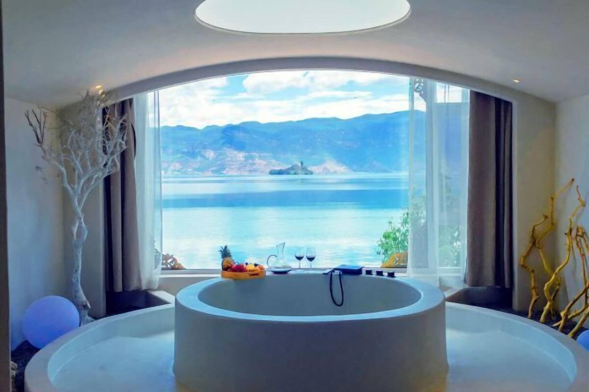Uma casa de banho moderna com uma banheira grande, vista para um lago e uma janela com cortinas.