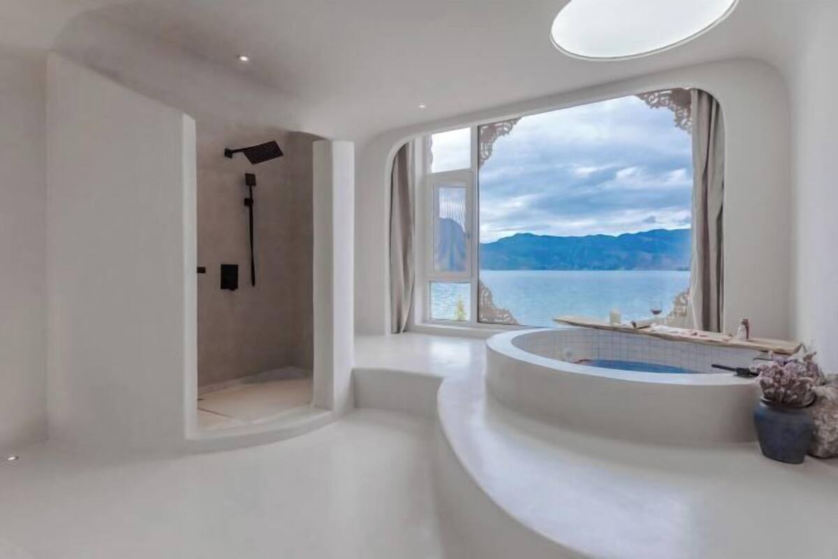 Casa de banho moderna com banheira, zona de duche e uma janela ampla com vista panorâmica.
