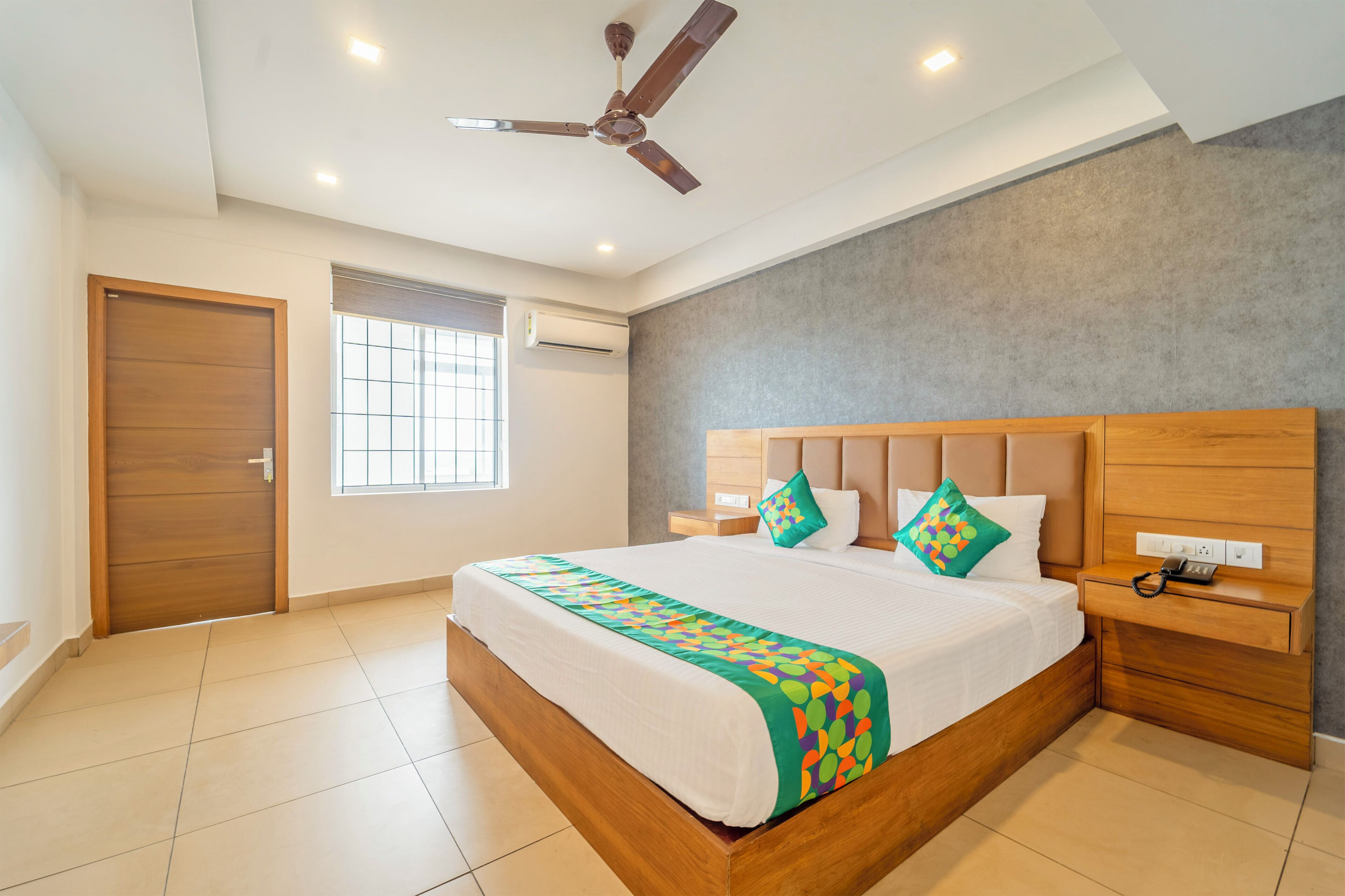 Quarto com cama de madeira, ventilador de teto, janela e ar-condicionado fixado na parede.