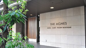 Fachada de um edifício com o nome "THE AGNES" e os serviços listados como HOTEL, CAFÉ e PASTELARIA.