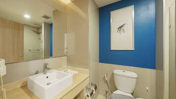 Casa de banho moderna com uma pia bege, sanita branca e parede azul decorativa.