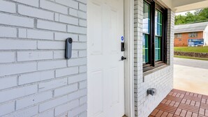 Um edifício de tijolos brancos com porta, janela, teclado numérico e placa azul.