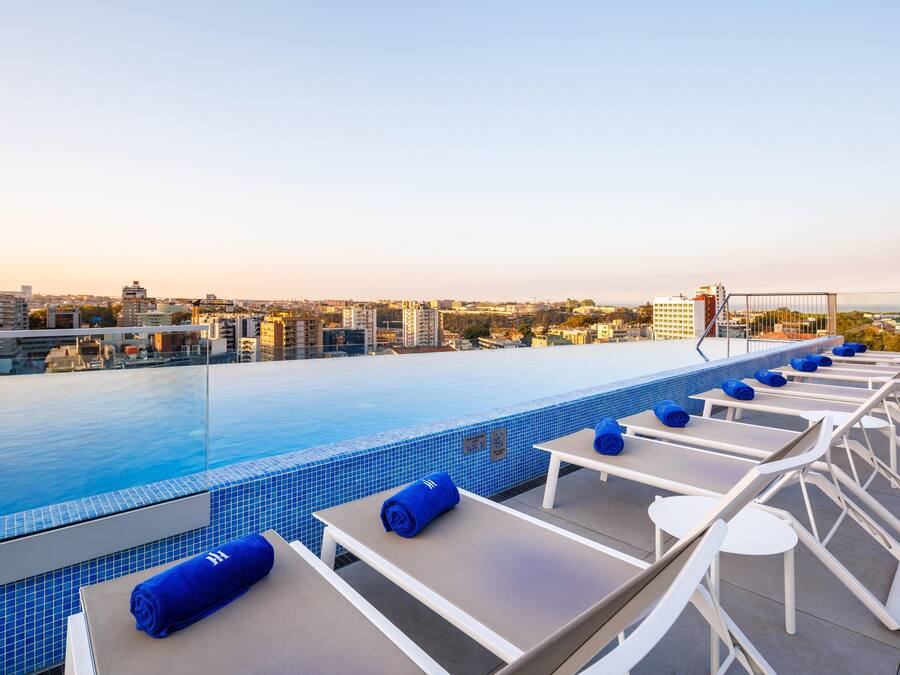 Área de piscina no terraço, com espreguiçadeiras e vista para a paisagem urbana.