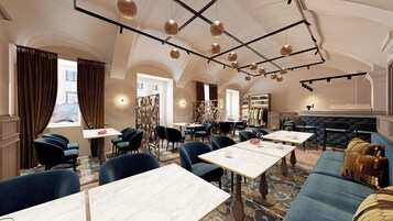 Um hall de hotel com mesas de mármore, assentos estofados em azul e teto decorativo com luminárias esféricas pendentes.