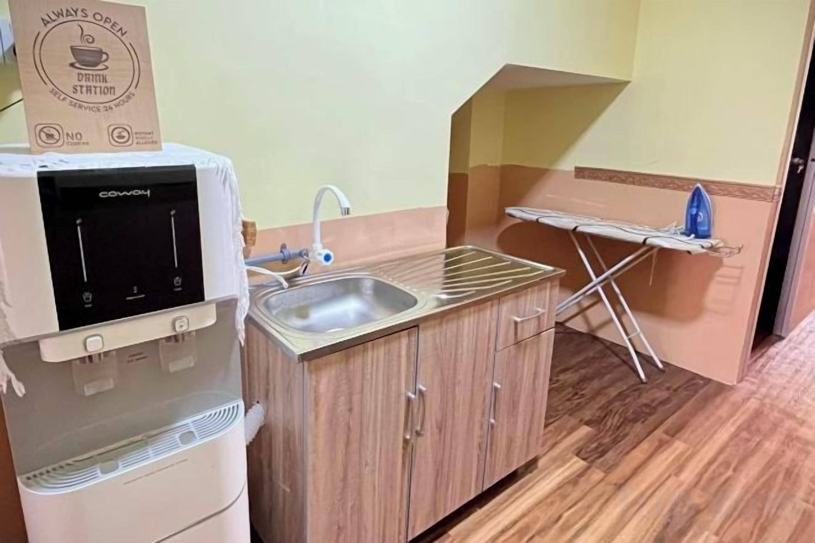 Cozinha compacta com máquina de café integrada, pia e suporte para louça.