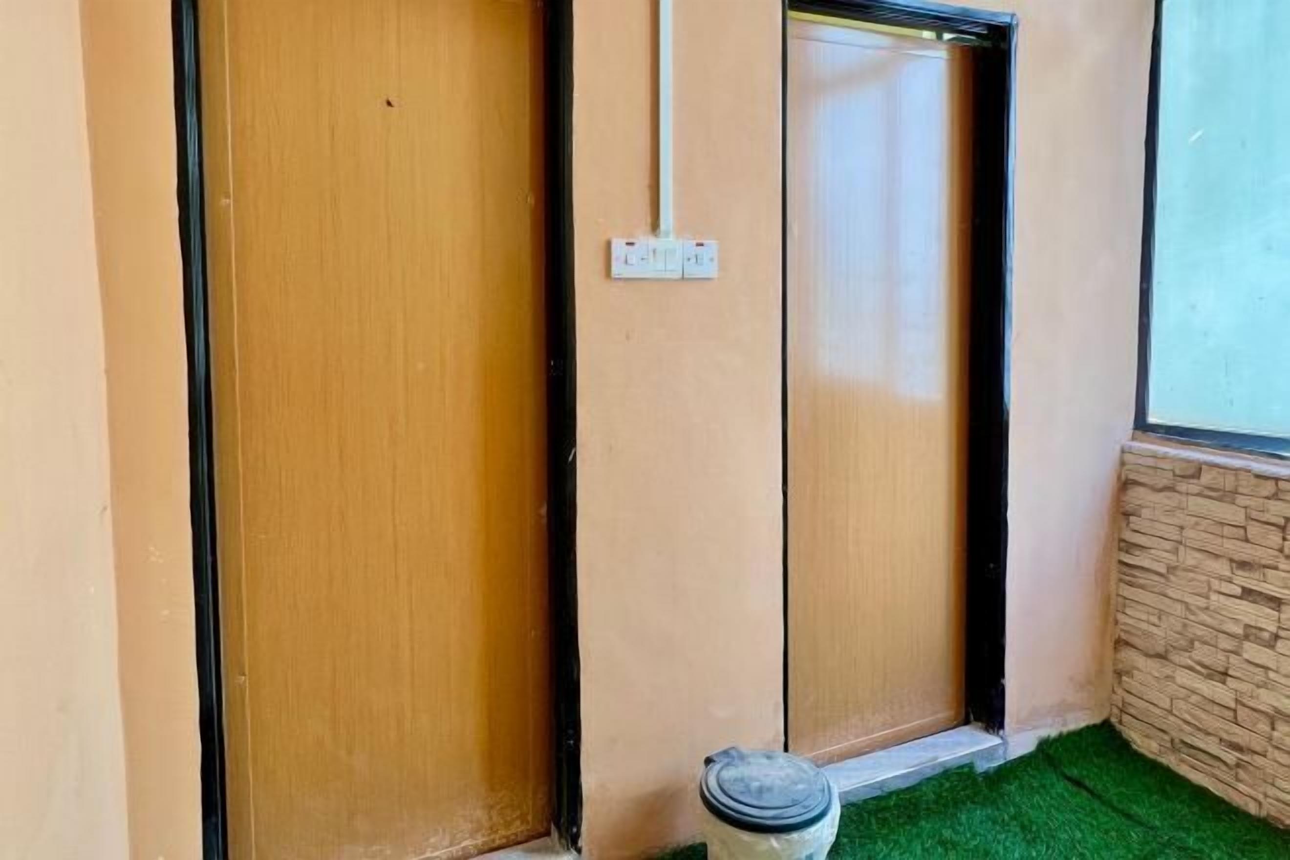 Uma porta de madeira com um painel de vidro, uma tomada e um pequeno recipiente no chão.
