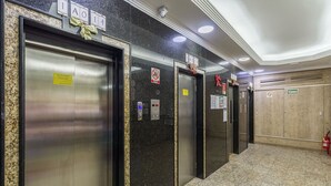 Um corredor com elevadores, cada um identificado por um número e uma placa indicando proibição de fumar.