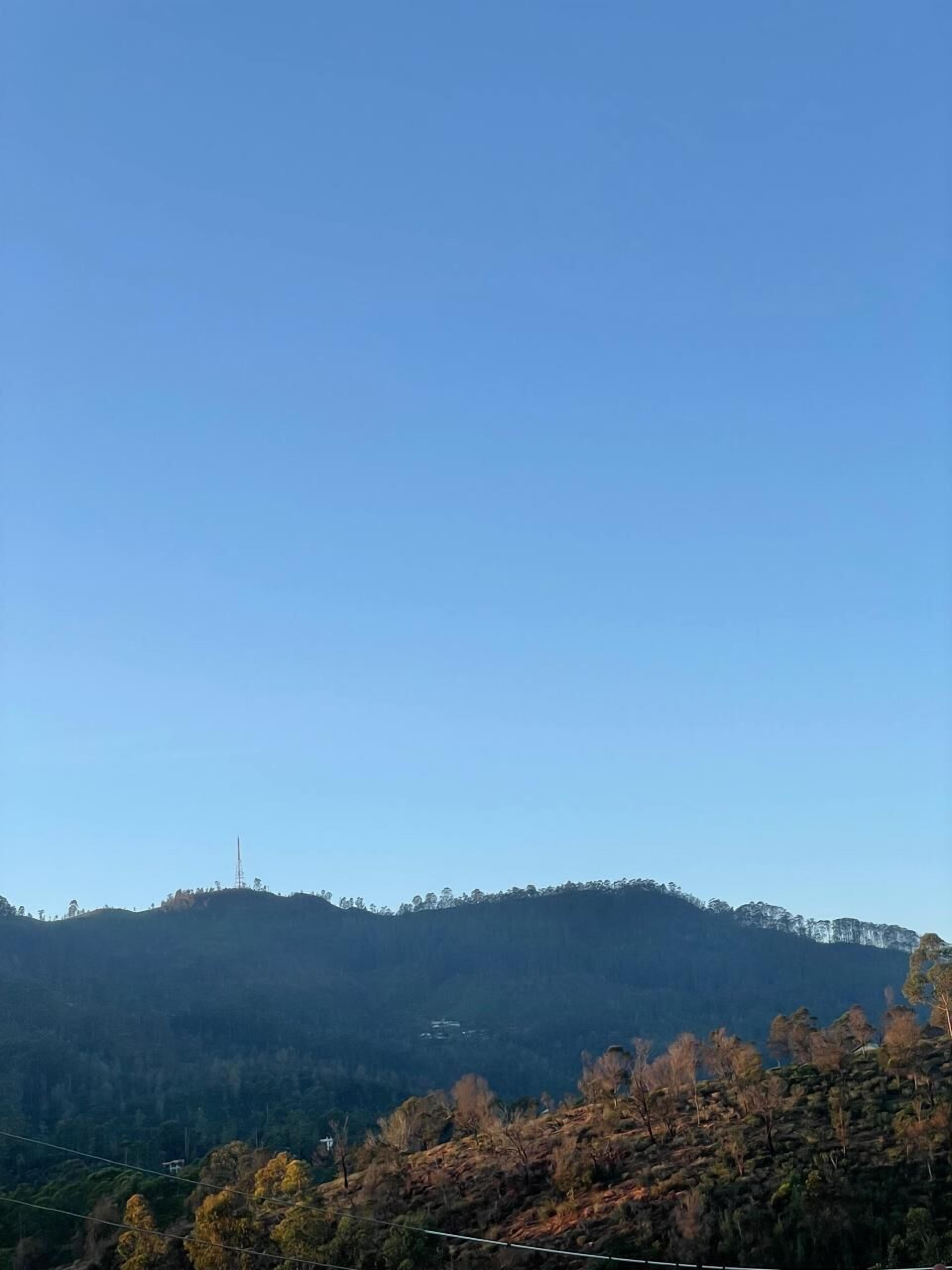 Visão ampla de uma paisagem montanhosa, com uma colina imponente ao fundo e uma área plana em primeiro plano.