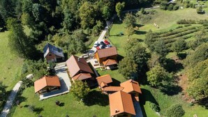 Uma área residencial com várias casas, cada uma com telhado de telhas vermelhas, cercada por vegetação exuberante e uma pequena estrada.