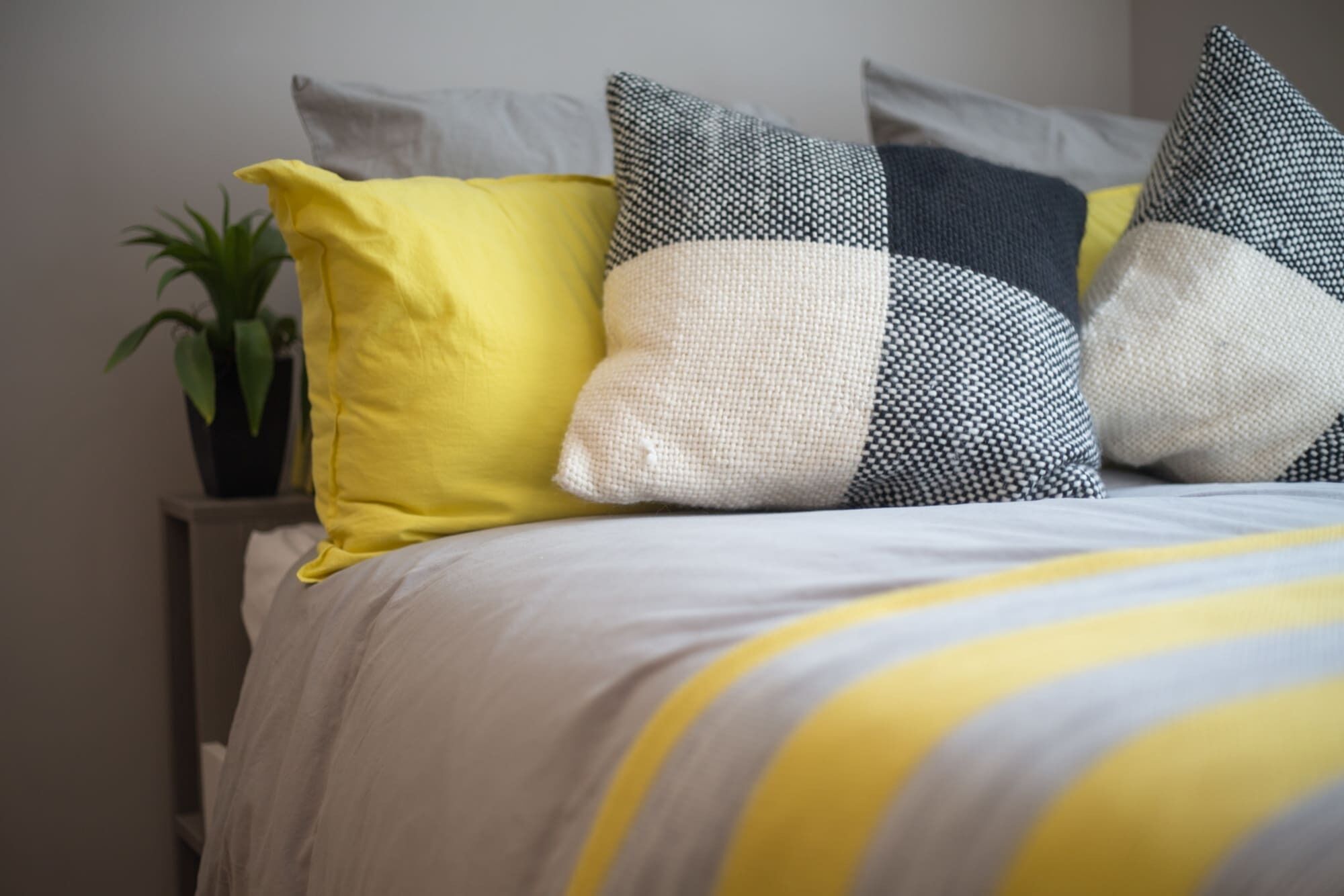 Uma cama com colcha listrada e várias almofadas em diferentes padrões e cores.