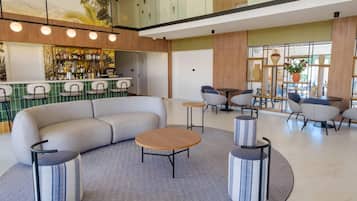Um lobby moderno com área de bar, assentos e pé-direito alto.