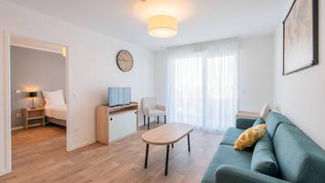 Uma sala de estar moderna com um sofá, uma mesa de centro, uma TV e uma pequena escrivaninha.