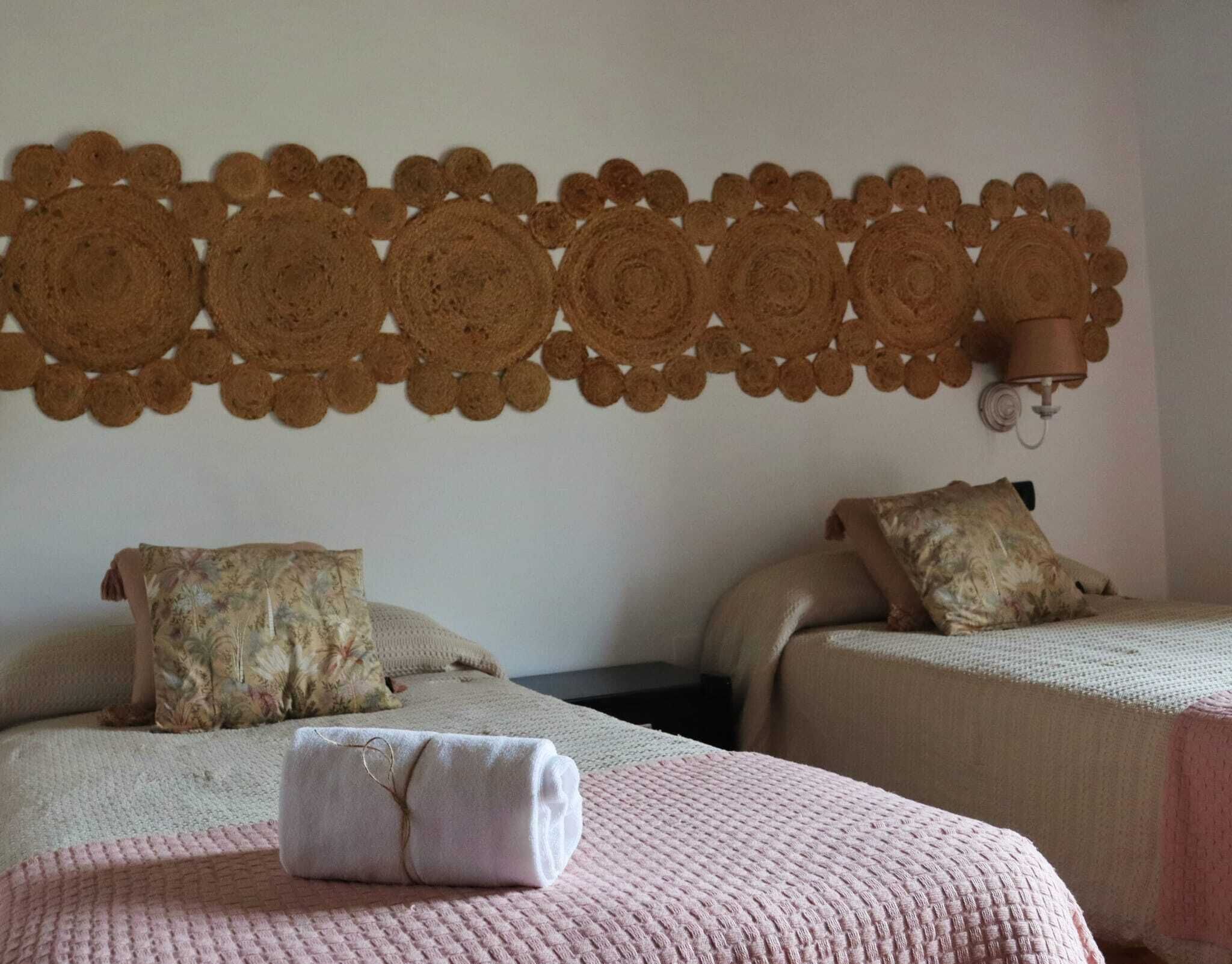 Quarto de hotel com duas camas, cada uma com travesseiro e toalha enrolada.