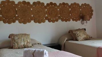 Quarto de hotel com duas camas, cada uma com travesseiro e toalha enrolada.