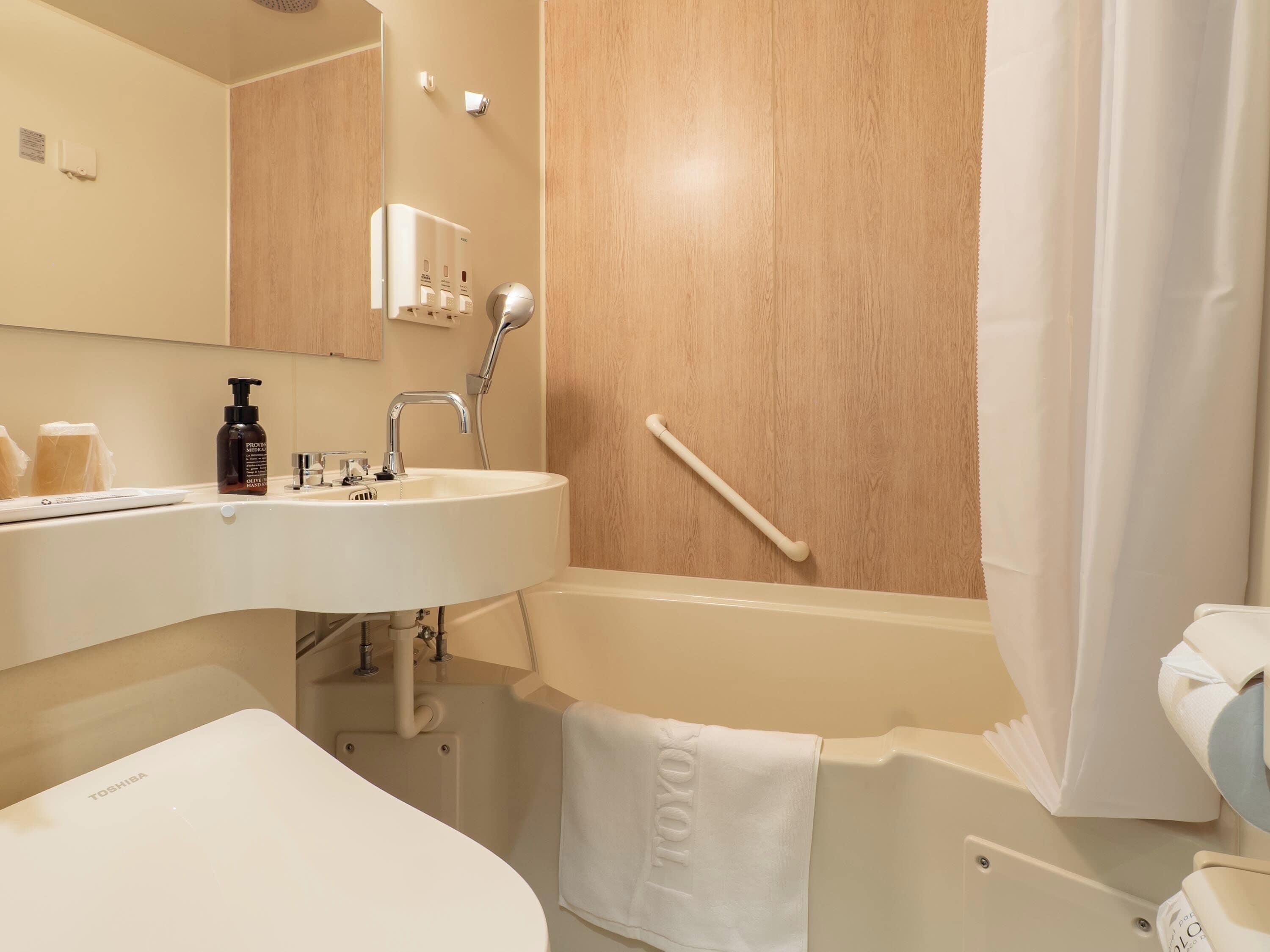 Uma casa de banho moderna com lavatório, espelho, chuveiro e um porta-toalhas.