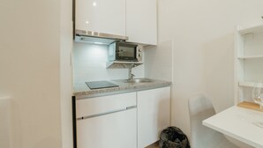 Uma cozinha compacta equipada com micro-ondas, pia e uma bancada pequena.