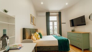 Quarto com cama, escrivaninha, televisão e guarda-roupa.