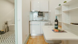 Uma cozinha moderna com armários brancos, um micro-ondas e uma garrafa de vinho no balcão.