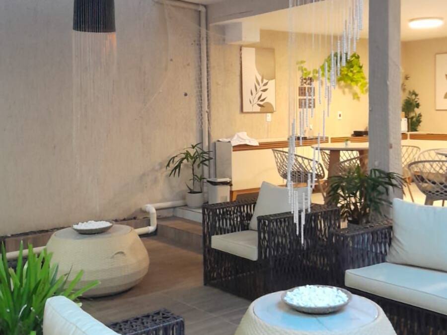 Uma área de estar externa com móveis de vime e luminárias pendentes.