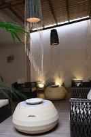Uma área de estar acolhedora com mobiliário de vime, um banquinho trançado e iluminação pendente.